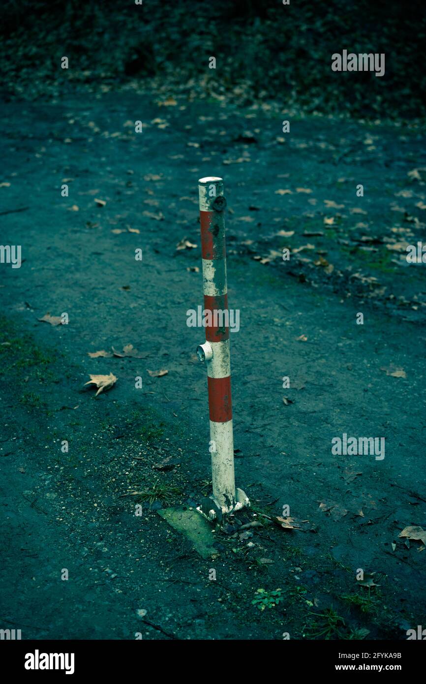 Vertical shot of a metal traffic pole with red lines on a grungy road ...