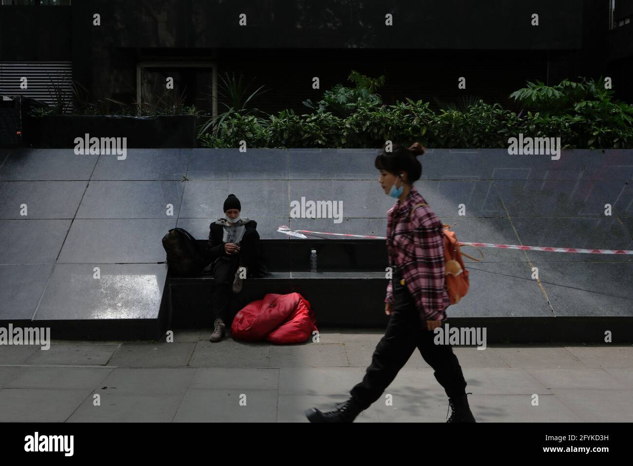 London (UK): A homeless woman with backpack and sleeping bag sits in a ...