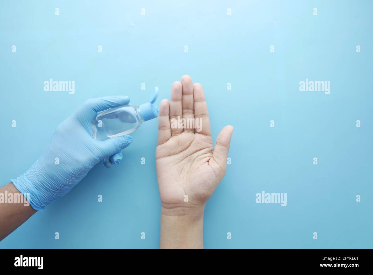 Using sanitizer liquid for preventing corona virus on blue background ...