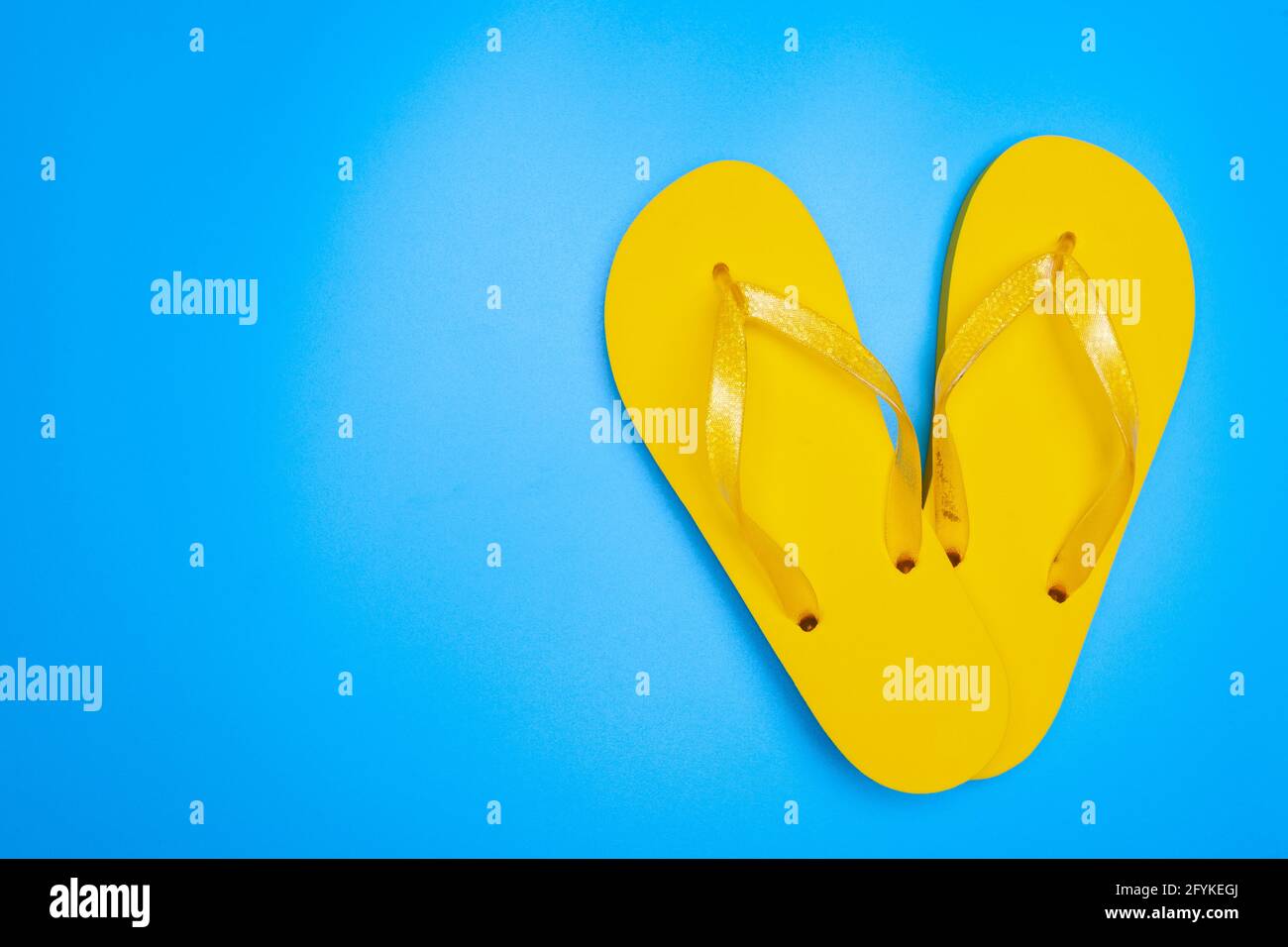 yellow rubber flip-flops isolated over blue background, pair of thongs ...