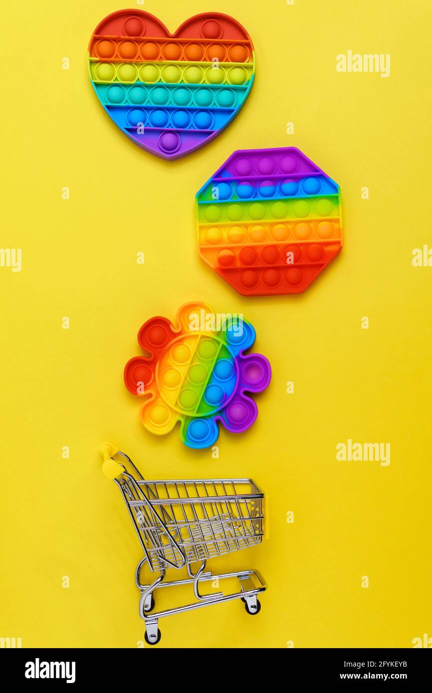 Colorful antistress sensory toy fidget push pop it. On a yellow ...