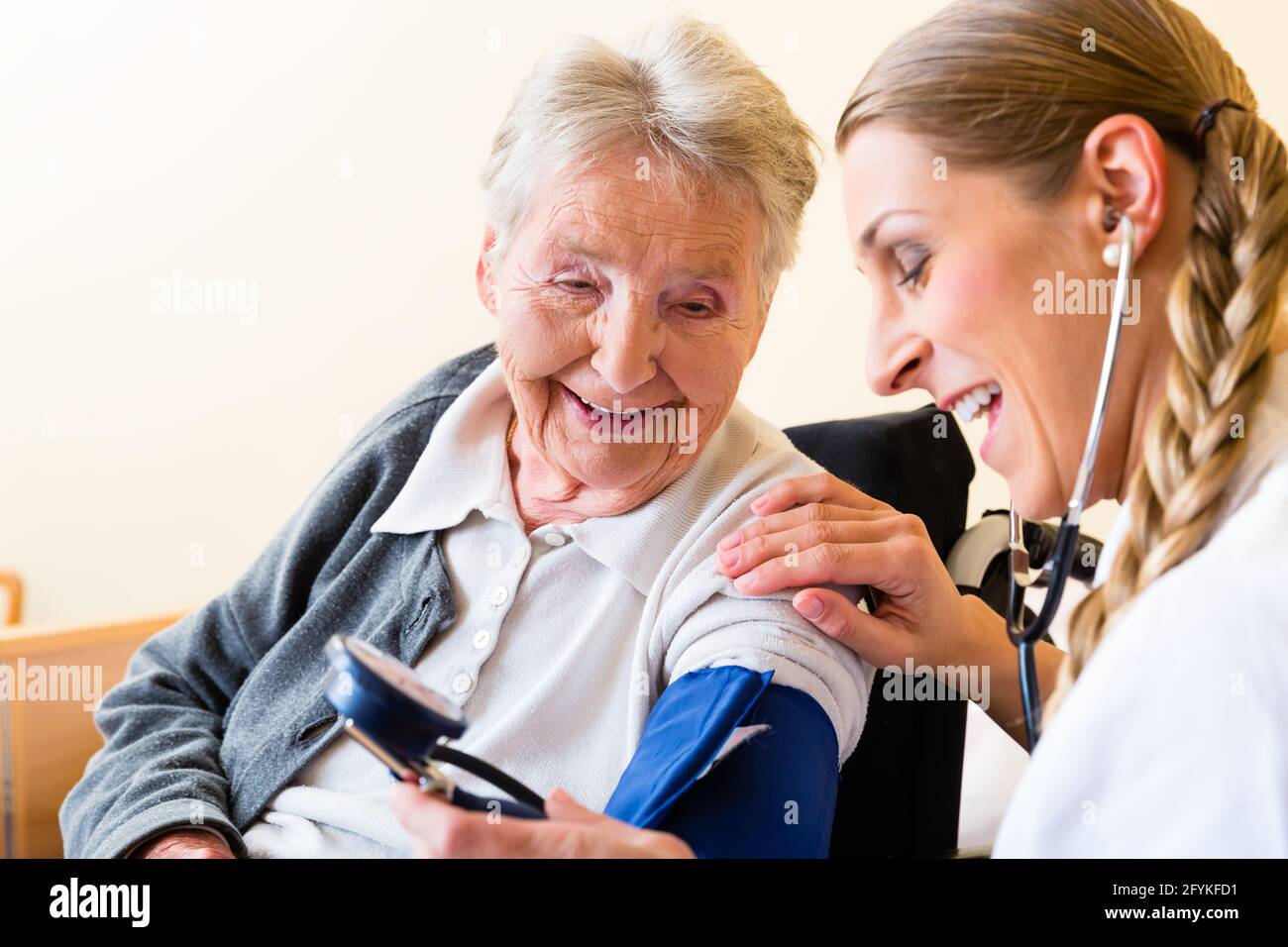 Nurse measuring blood pressure at senior woman patient in retirement ...