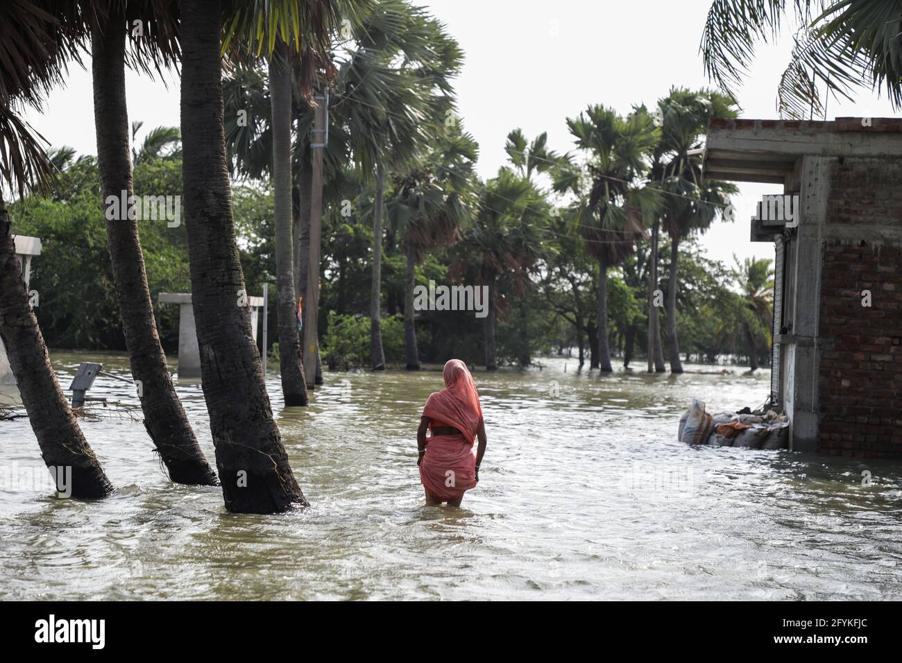 A lady walks through the flood water in a flood-hit coastal village ...