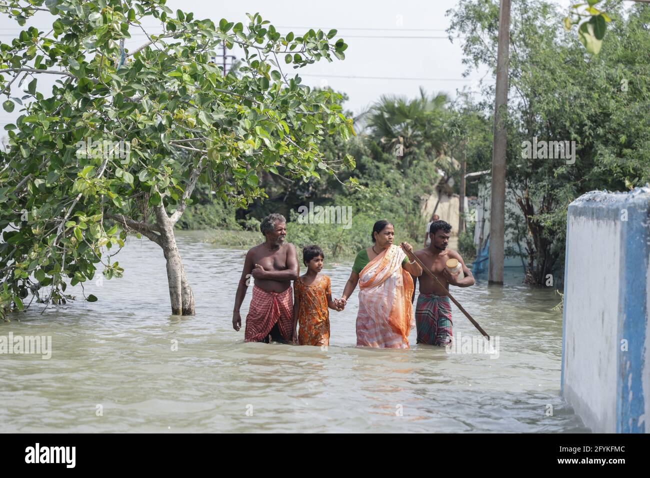 A family walking through the flood water of a coastal village during ...