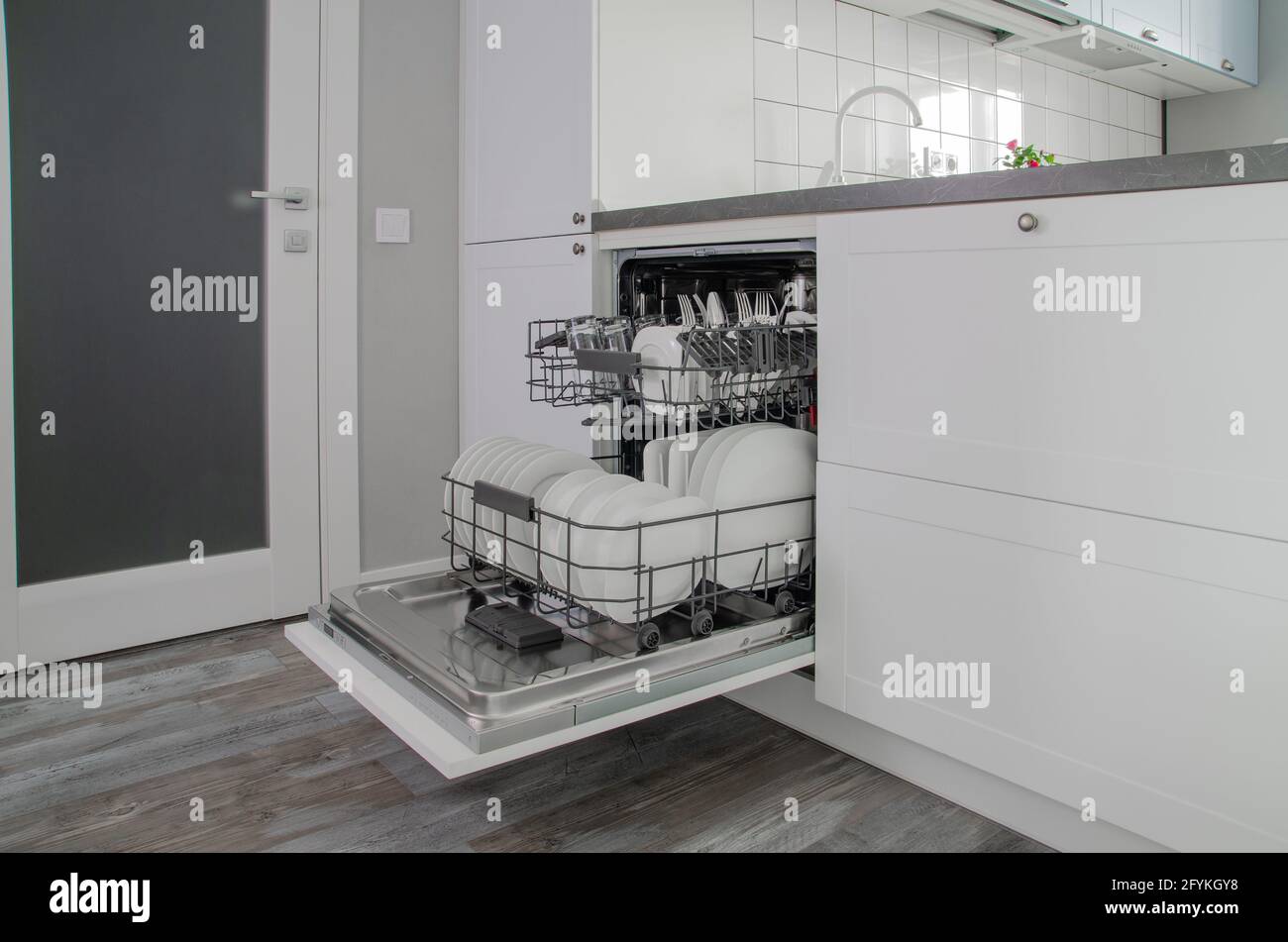 Open dishwasher with white clean dishes after washing in modern ...