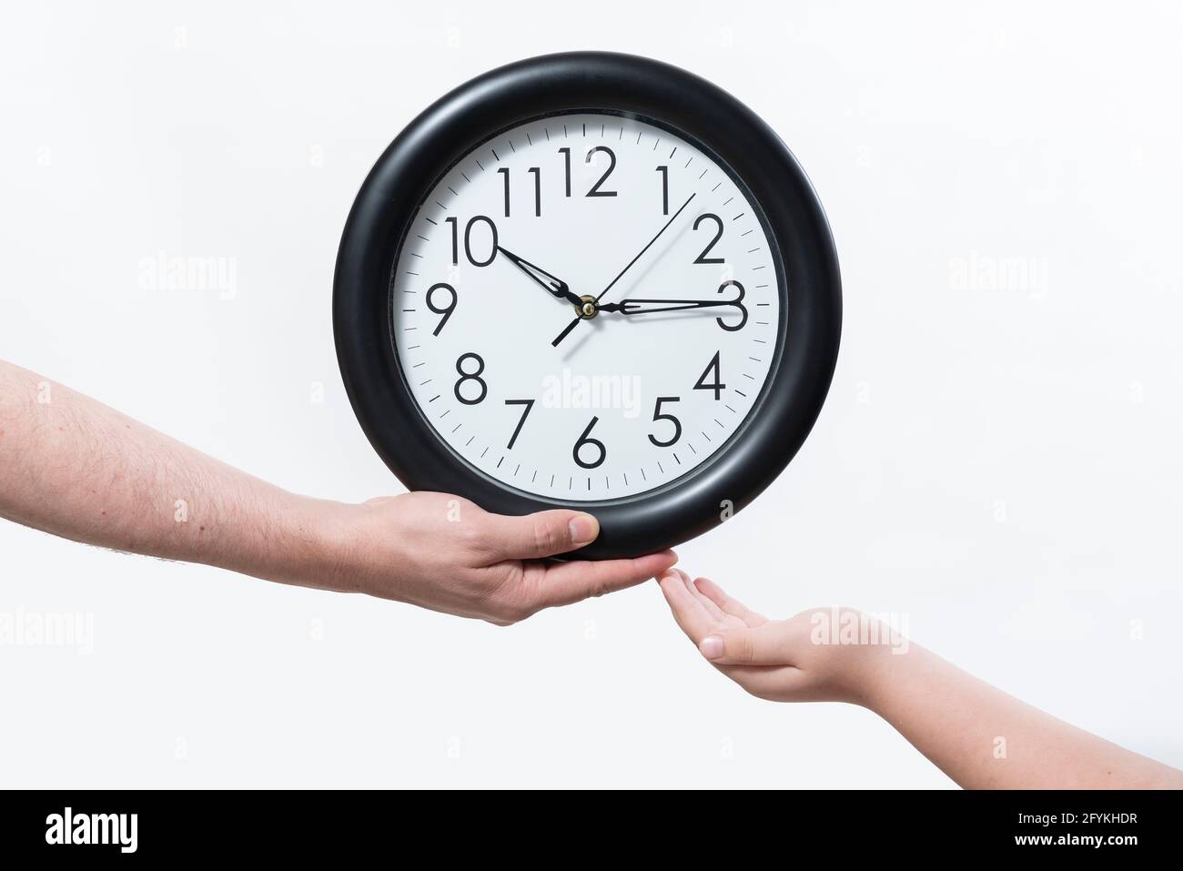 male hand handing a wall clock to boy's hand, isolated on white ...