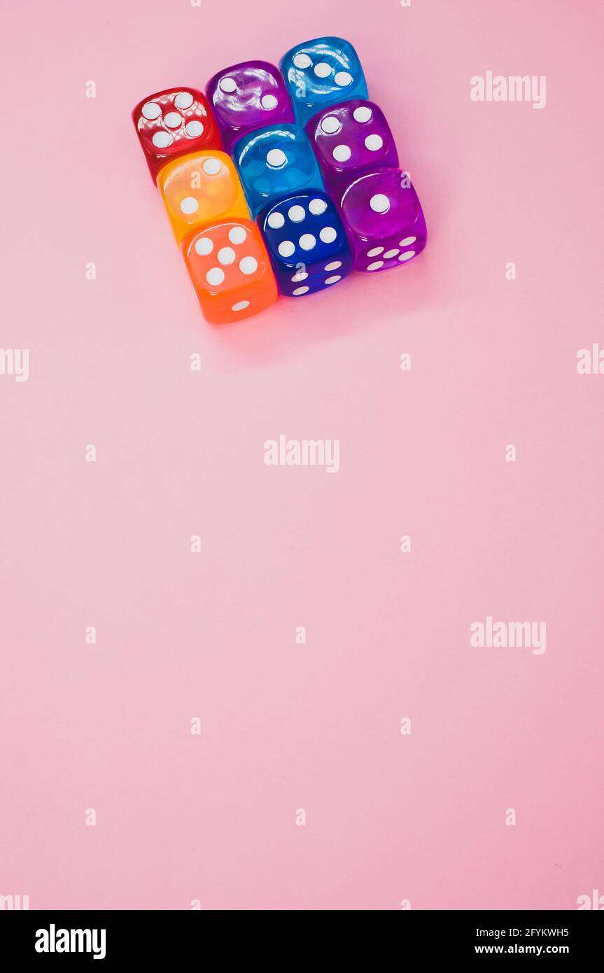 Vertical shot of a cube made of colorful dice isolated on a pink ...