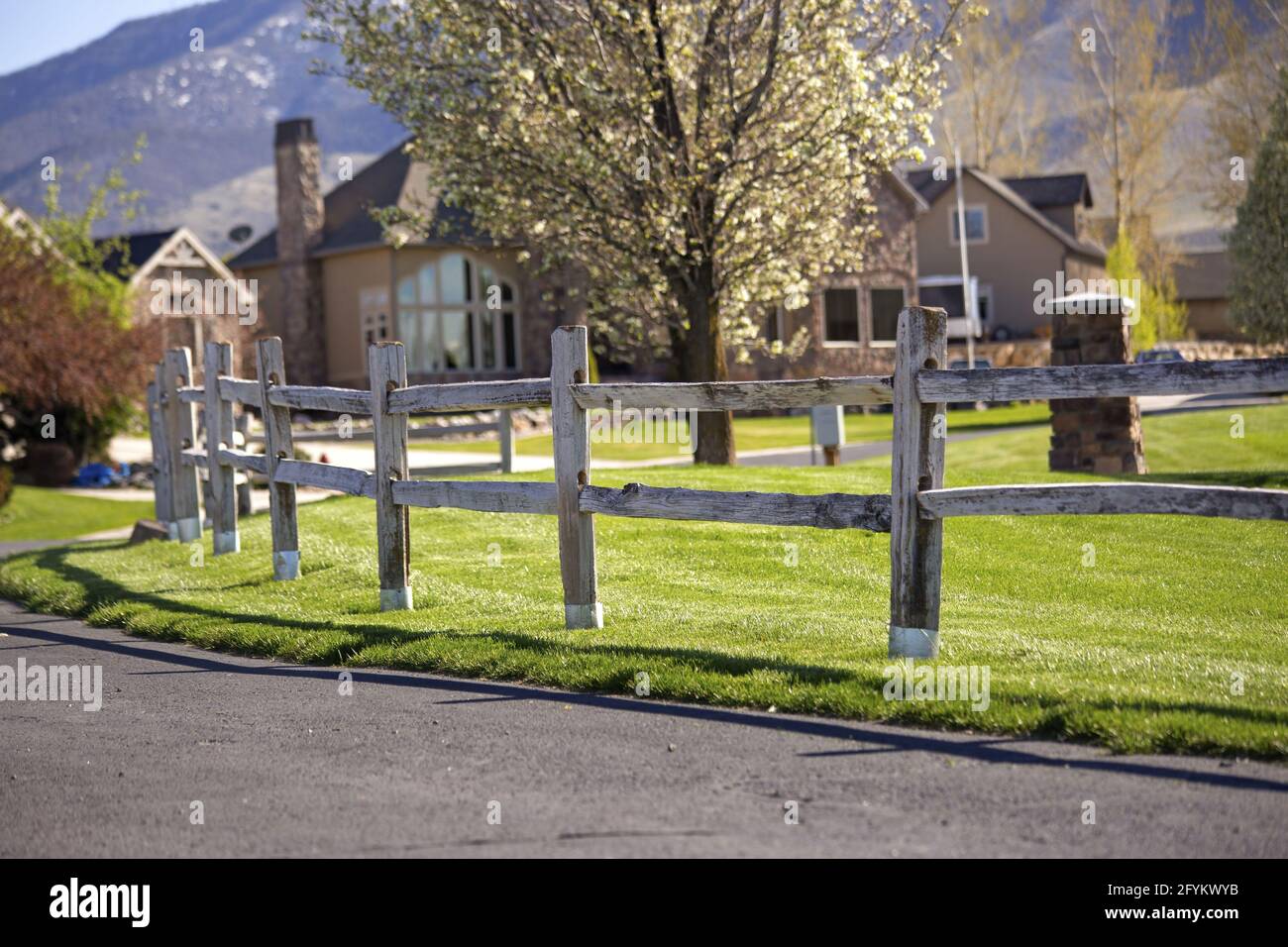 Ranch style wooden fence surrounding a green field in the countryside ...