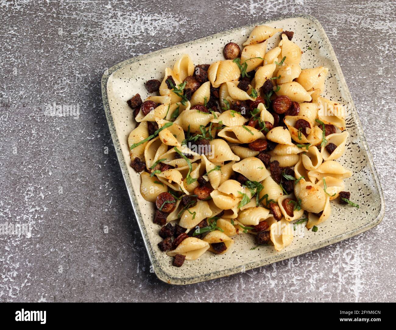 Pasta with sausages and bread crumbs on a rectangular plate on a dark ...