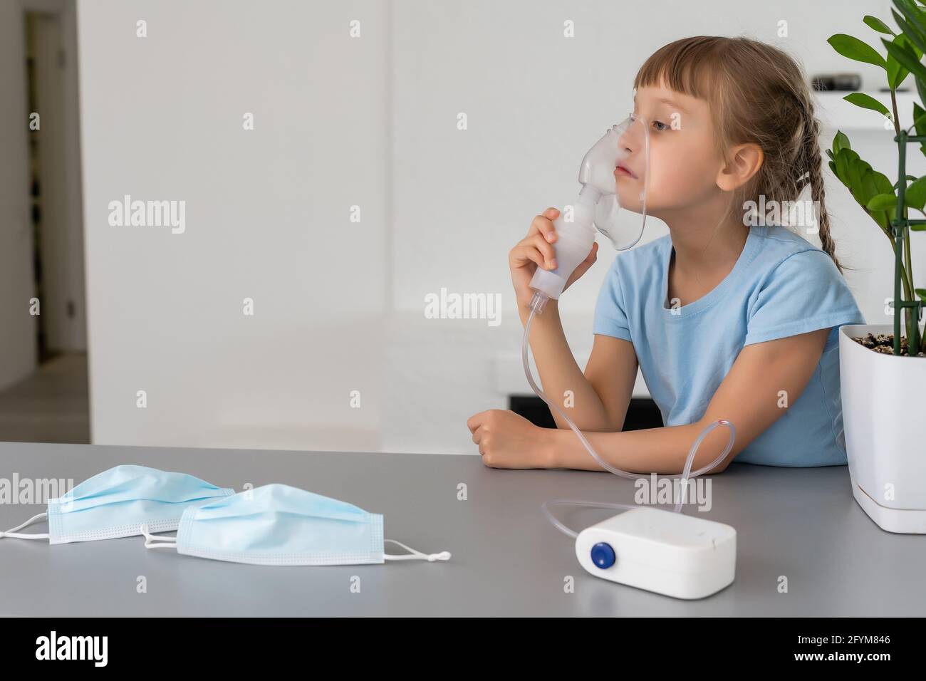 sick little girl makes inhalation over grey background with copy space ...