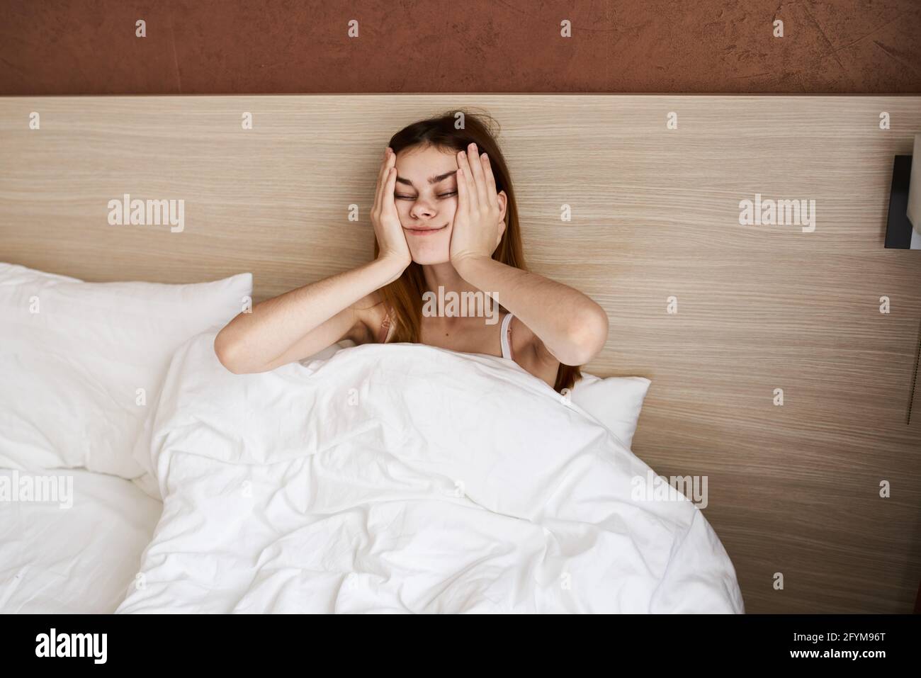 woman woke up early in the morning and touch her face with her hands ...