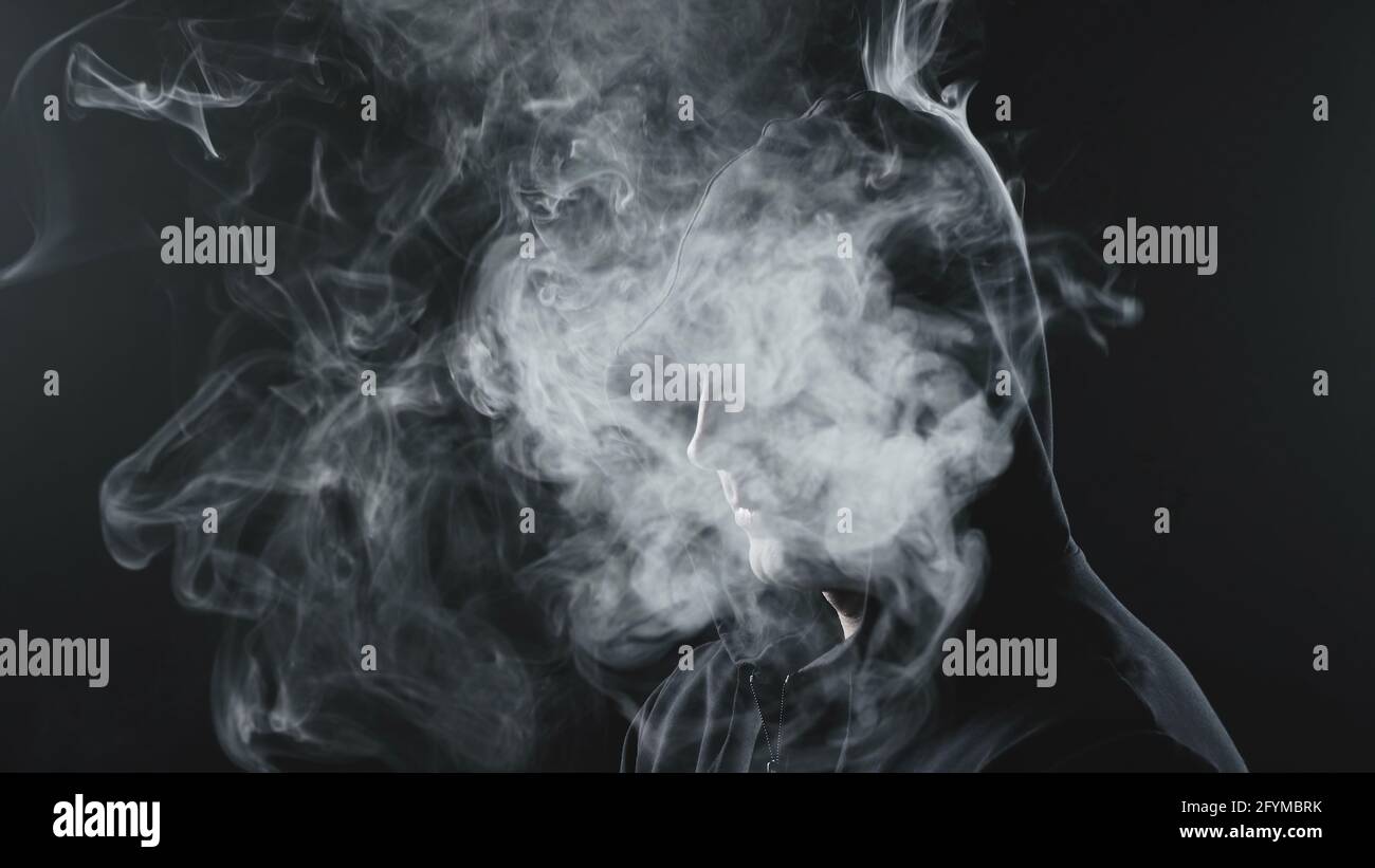 Man in black hood with the smoke inside Stock Photo - Alamy