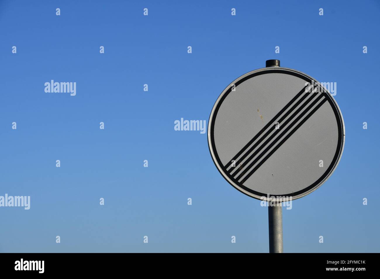 german round traffic sign repealing any speed limit in front of blue ...