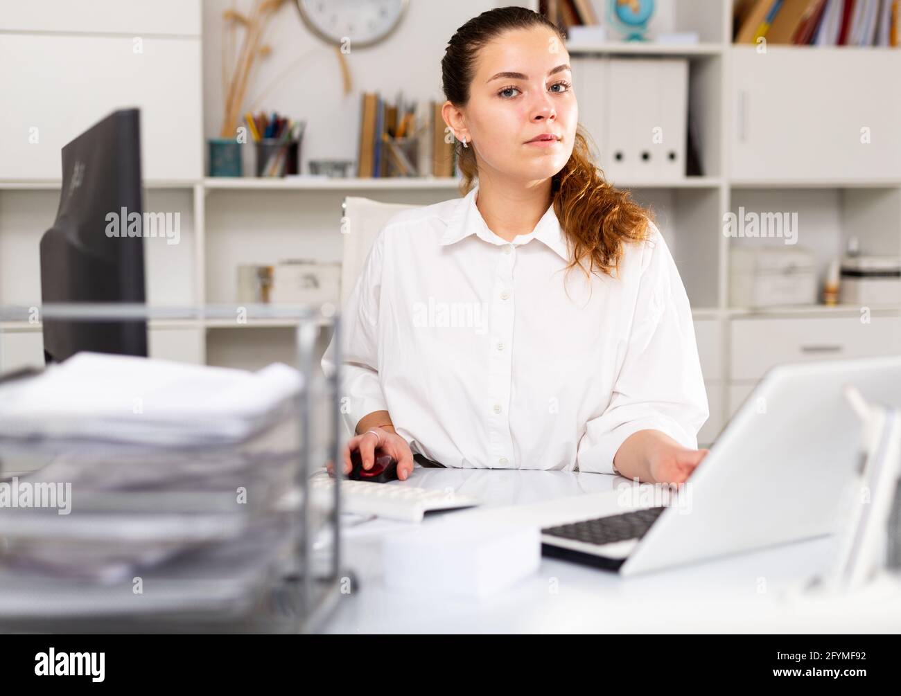 Focused young woman secretary working alone at her workplace on laptop ...