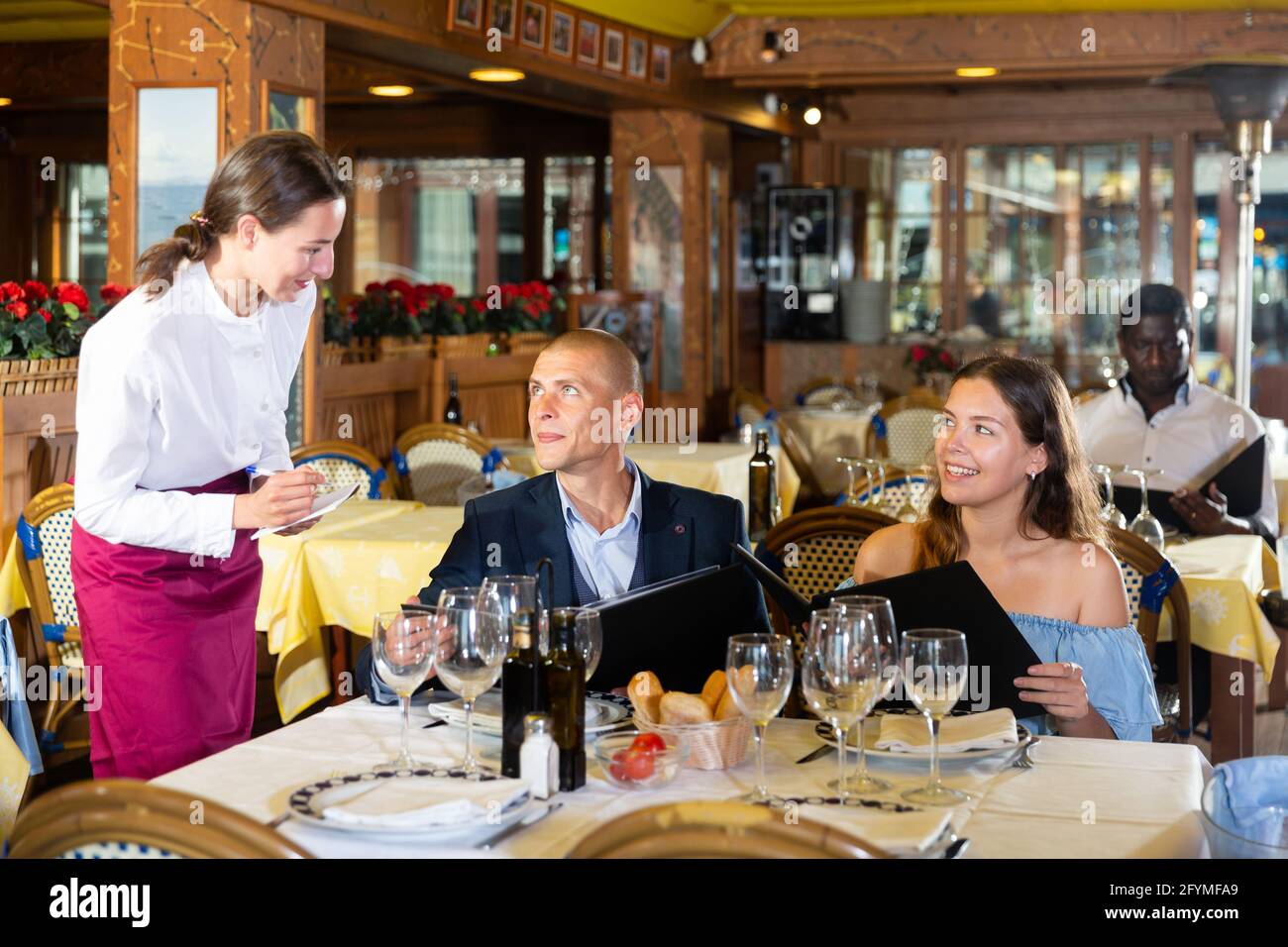 Diligent female waiter bringing order to visitors in restaurant Stock ...