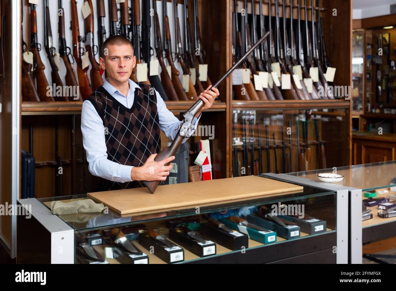 Portrait of gun store salesman showing collectible old rifled musket on ...