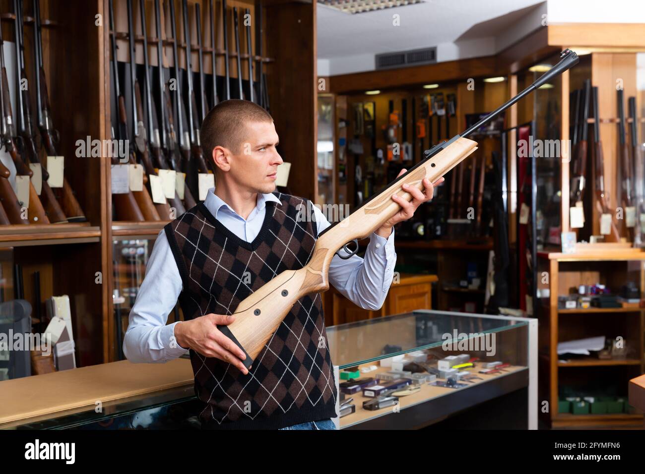 Gun shop salesman with air rifle in hand Stock Photo - Alamy