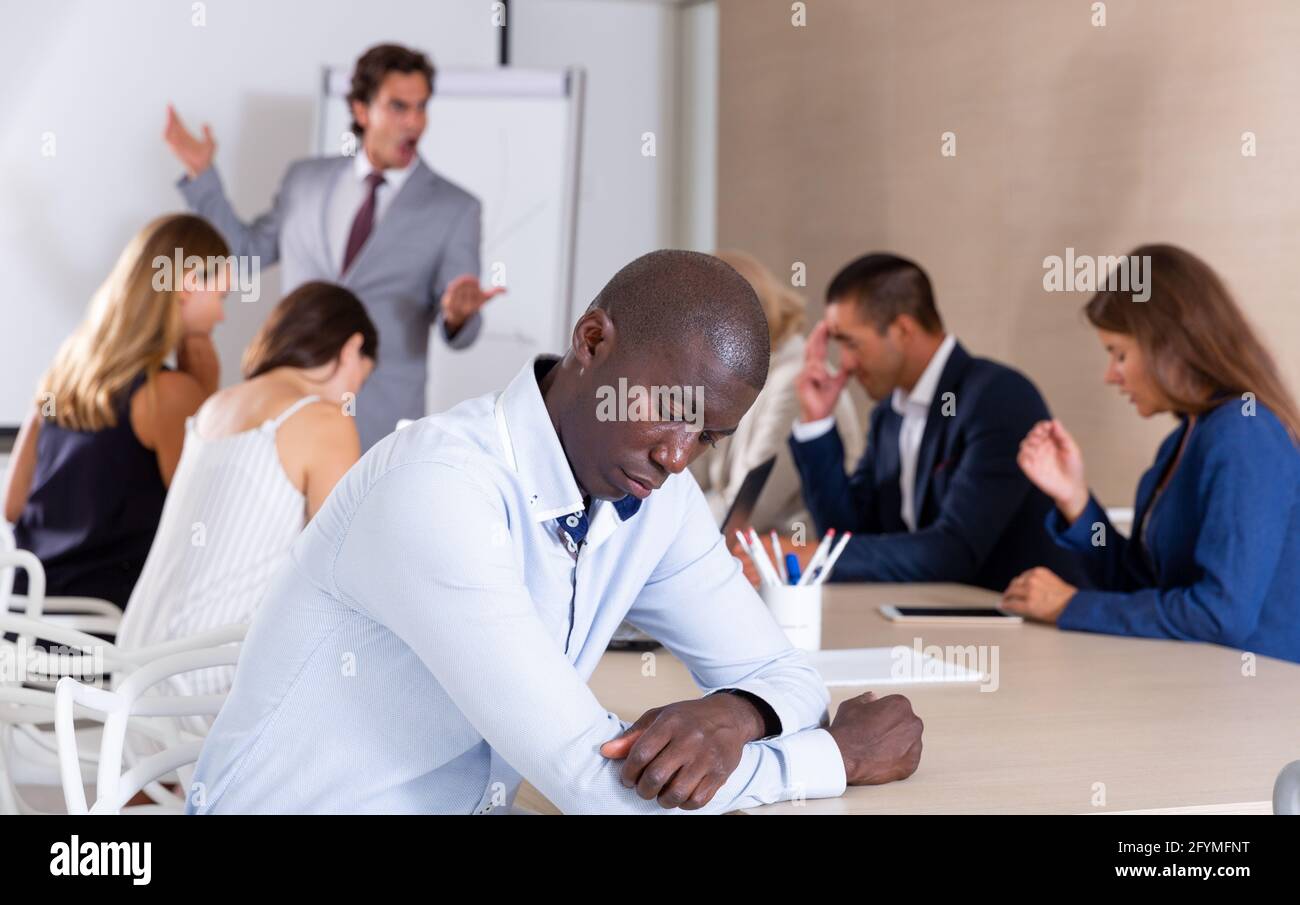 Upset Afro male office worker on meeting with colleagues and angry boss ...