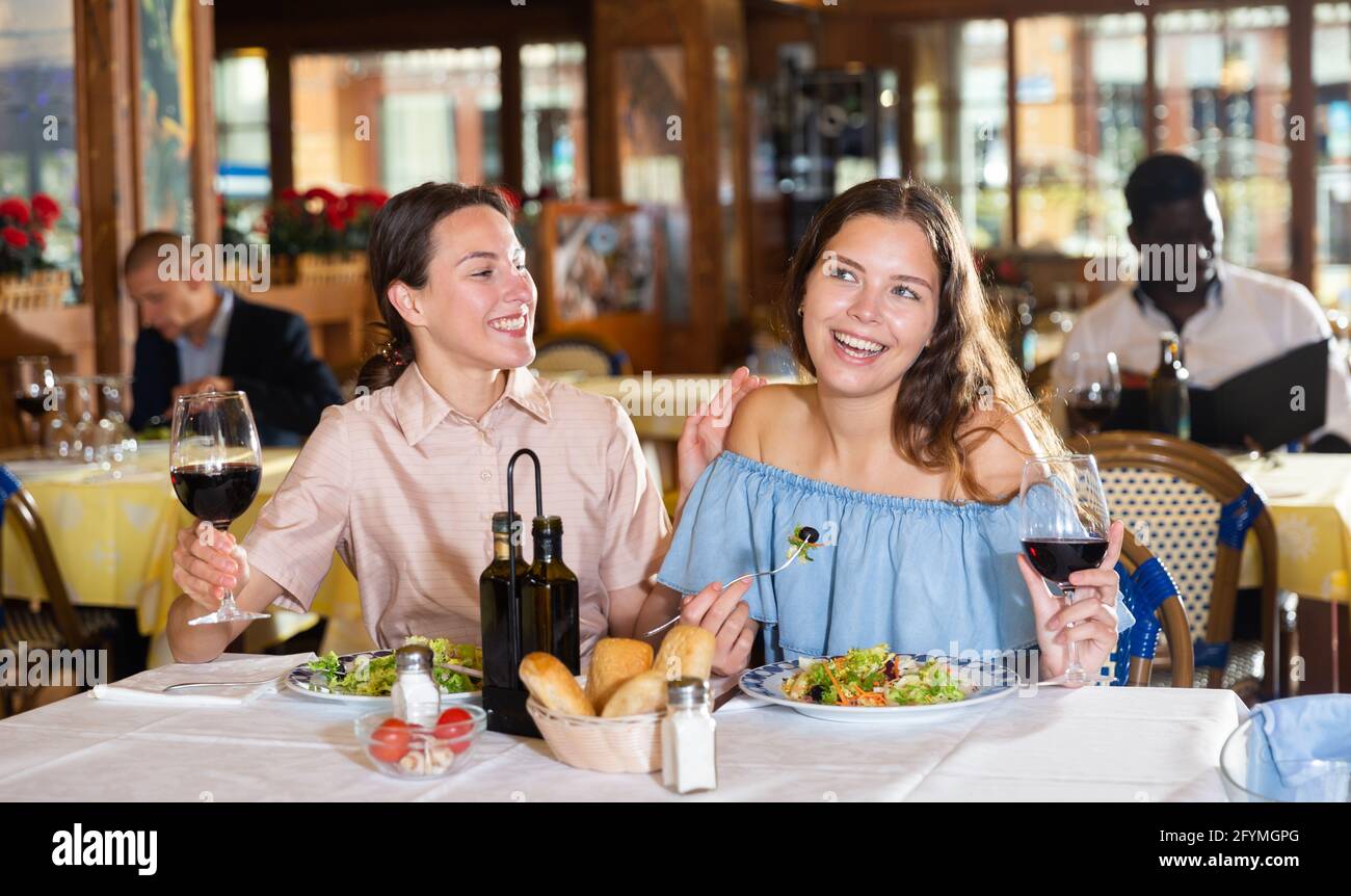 Two cheerful women friends enjoying evening meal in restaurant Stock ...