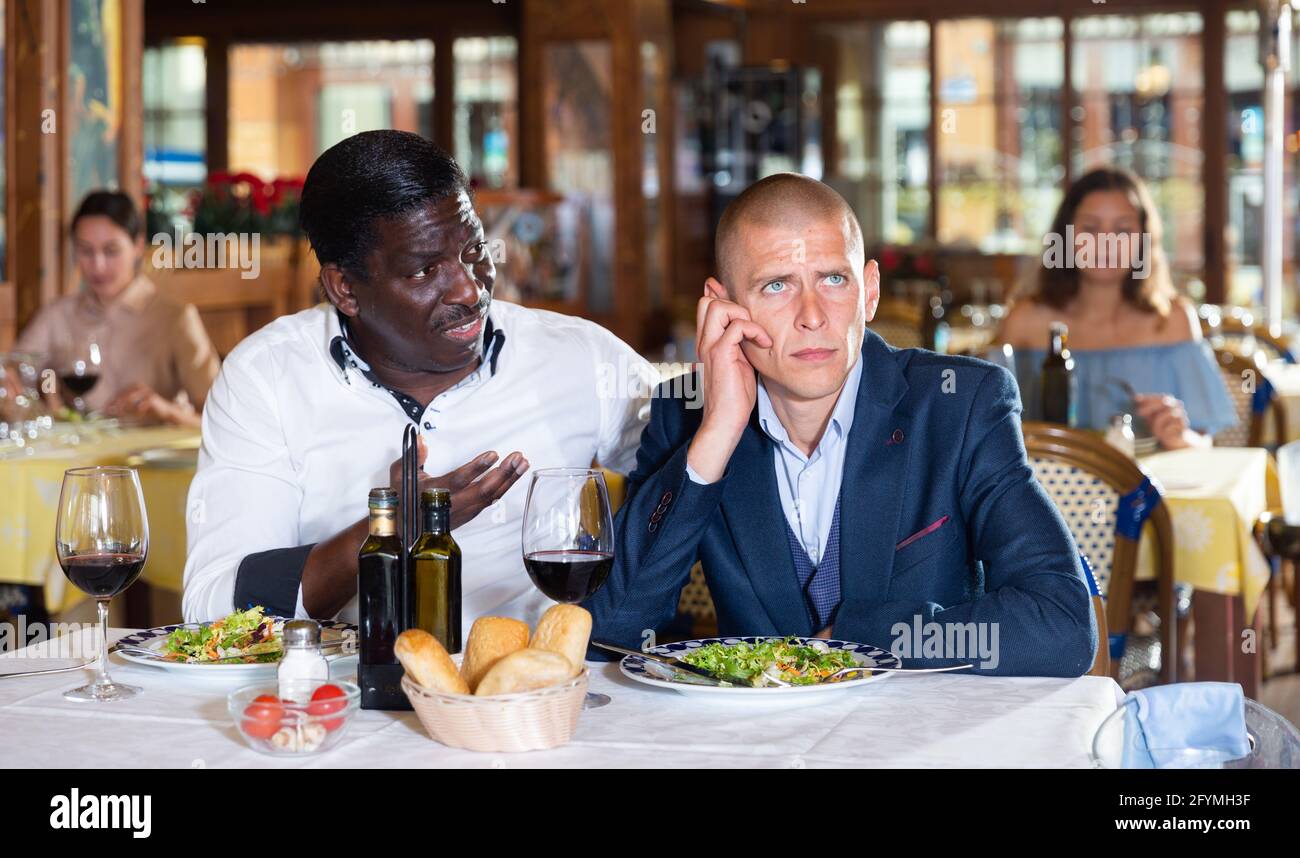Man talking with upset friend during dinner at restaurant Stock Photo ...