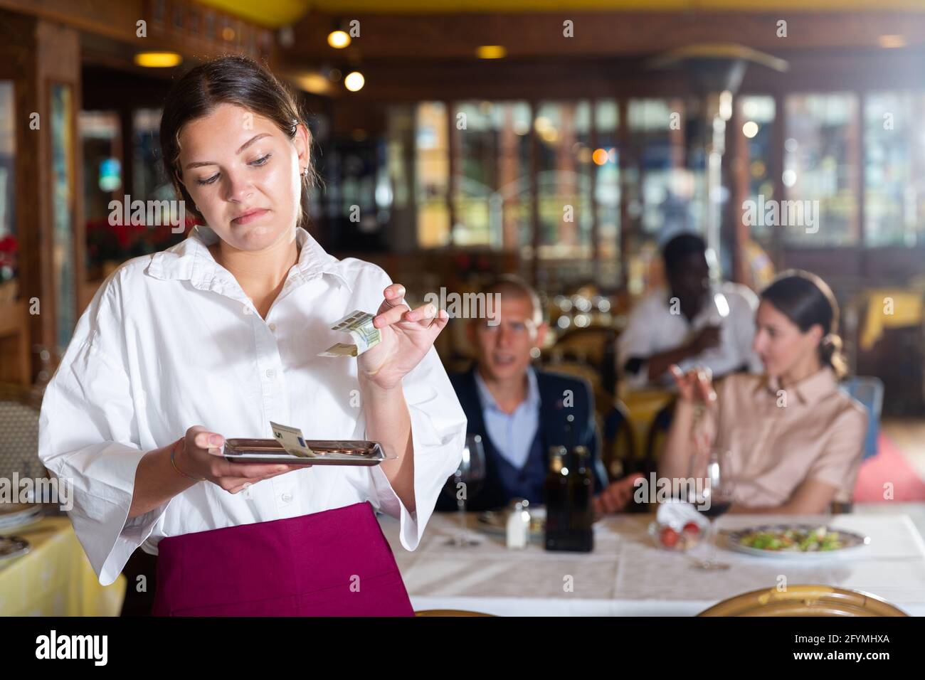 Discontented young waitress received small tips standing with money in ...