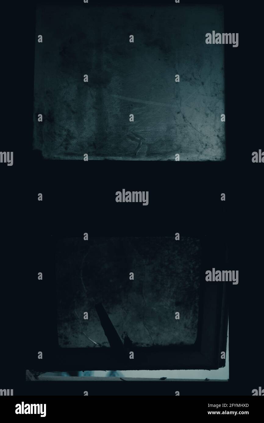 Vertical shot of a blueish half-opened window with scratch marks on the ...