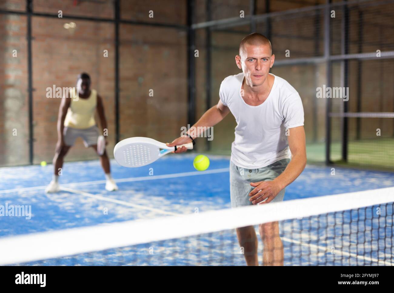 Portrait of concentrated paddle tennis player preparing to hit forehand ...