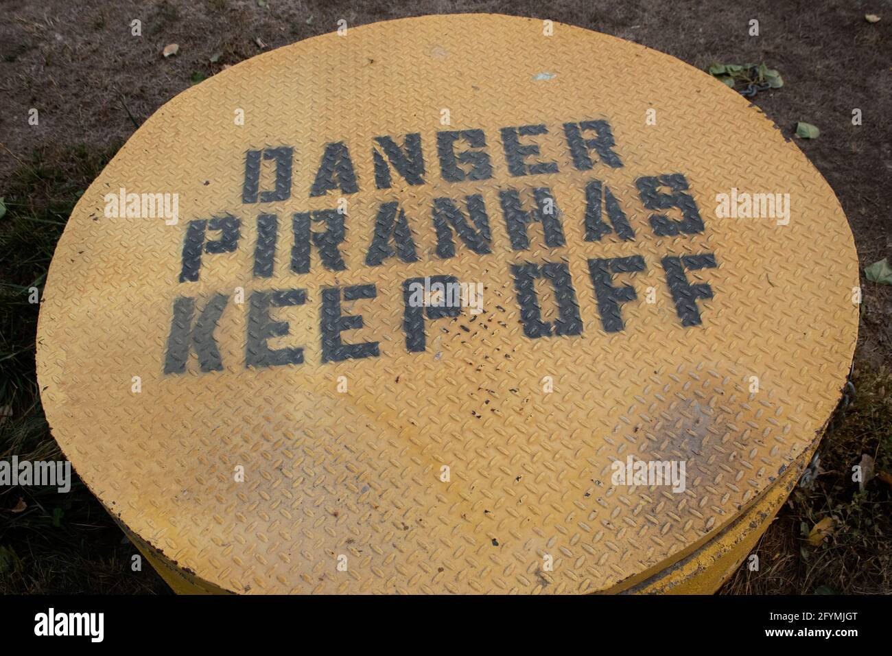 Manhole cover with a sign on it saying 'danger piranhas keep off' Stock ...