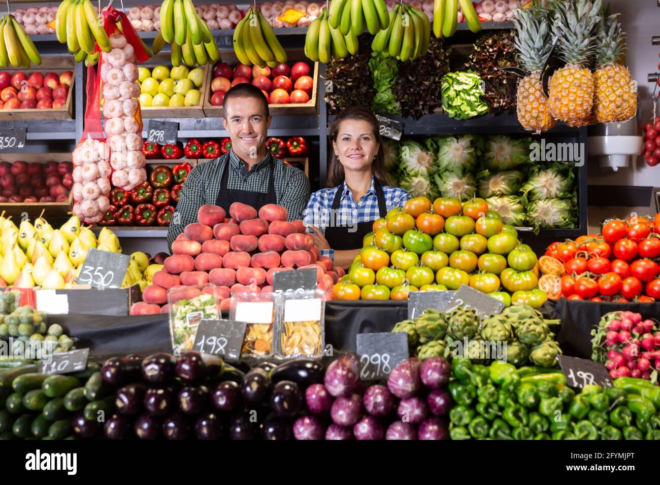 Positive male and female shop assistants in vegetable shop Stock Photo ...