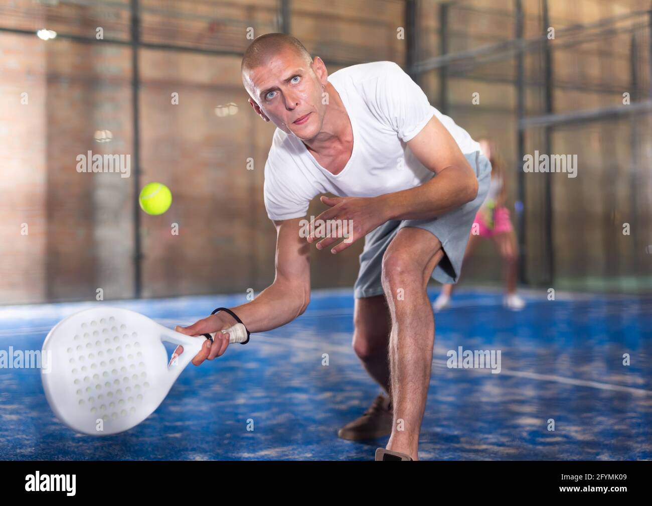 Padel player playing padel in a padel court indoor behind the net Stock ...