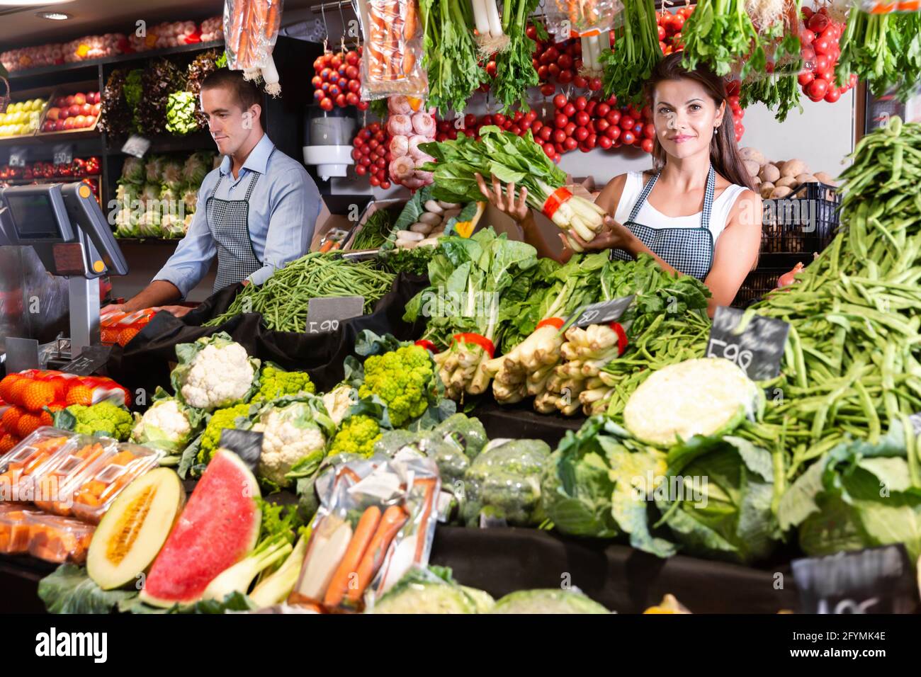 Portrait of diligent cheerful smiling female and male vegetable shop ...