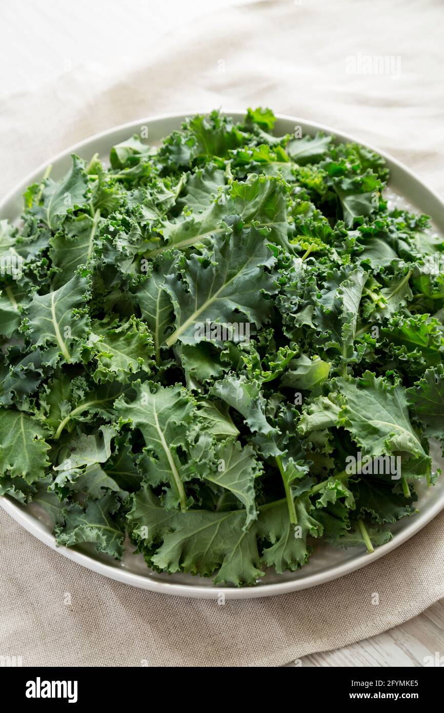 Raw Organic Baby Kale on a gray plate on a white wooden background ...