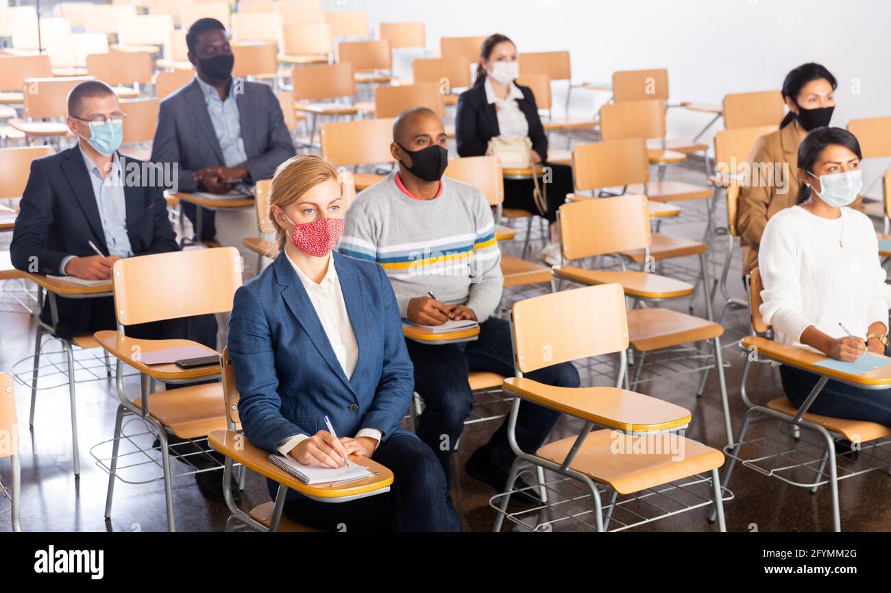 Multiethnic group of people wearing protective masks sitting in ...