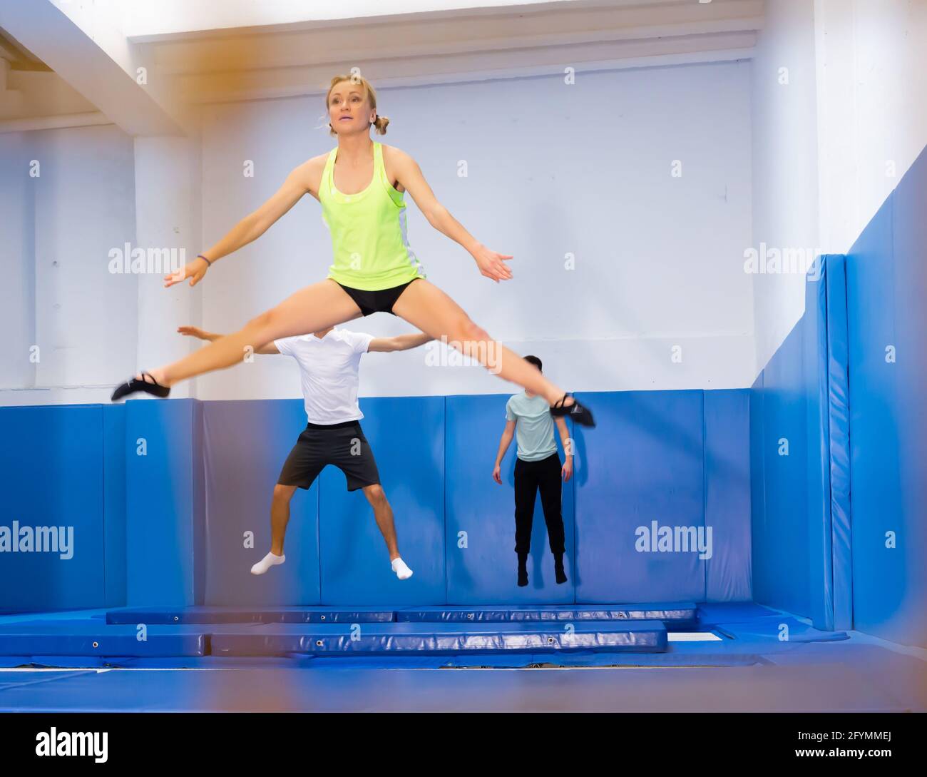 Female gymnast jumping on professional trampoline, practicing middle ...