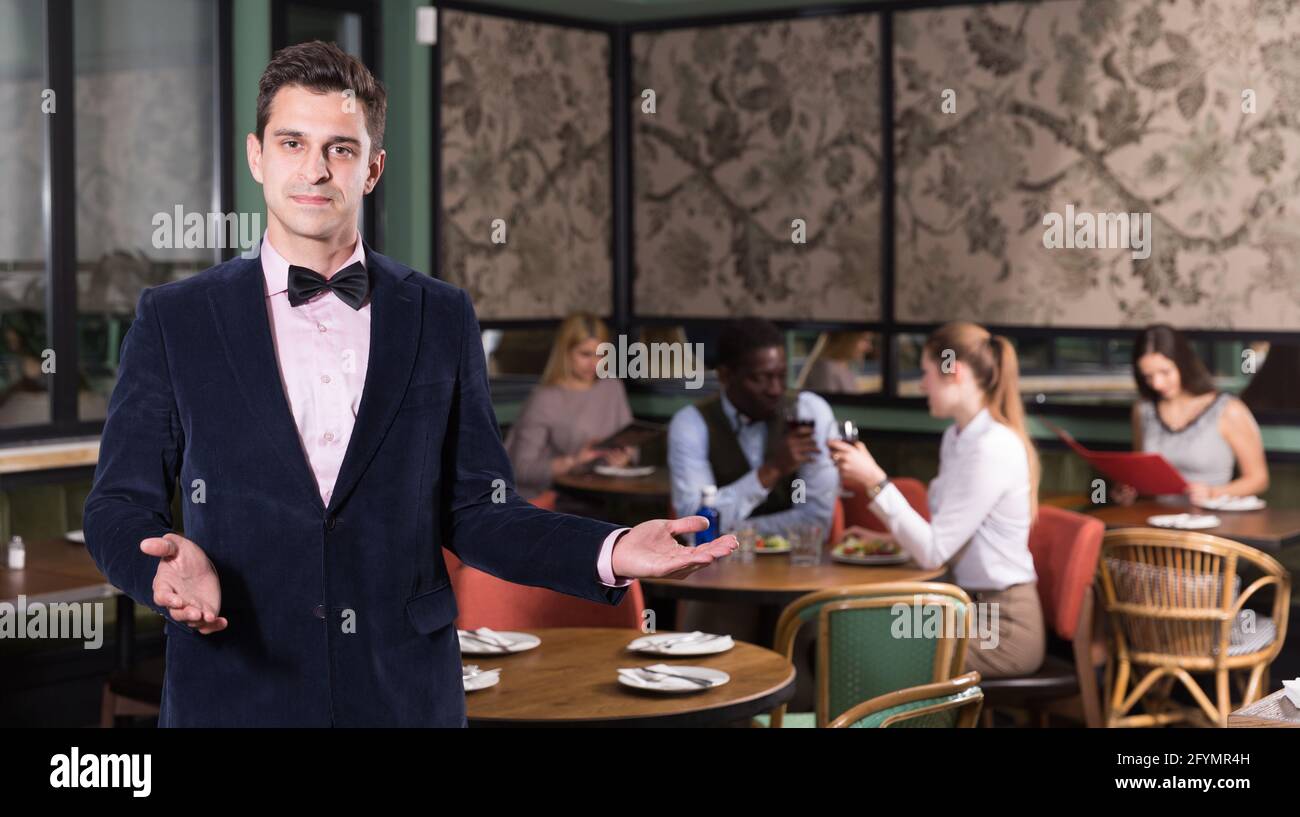 Handsome elegant waiter standing with welcome gesture in restaurant ...