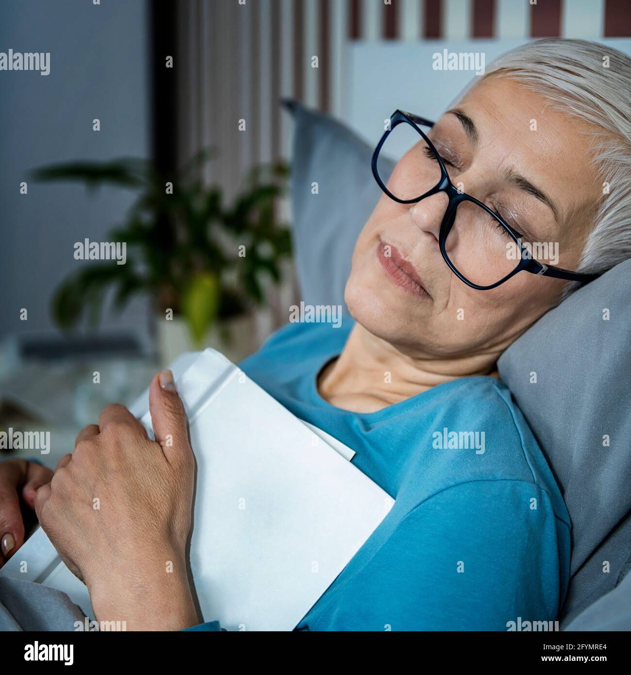Senior woman falling asleep reading Stock Photo - Alamy