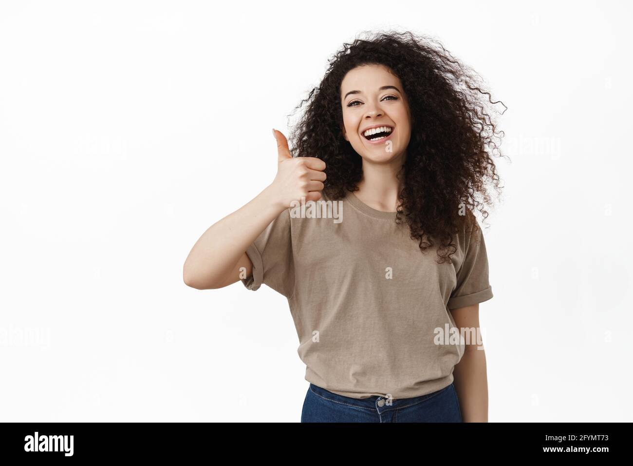 Very good. Cheerful brunette girl smiling, nod in approval, show thumbs ...