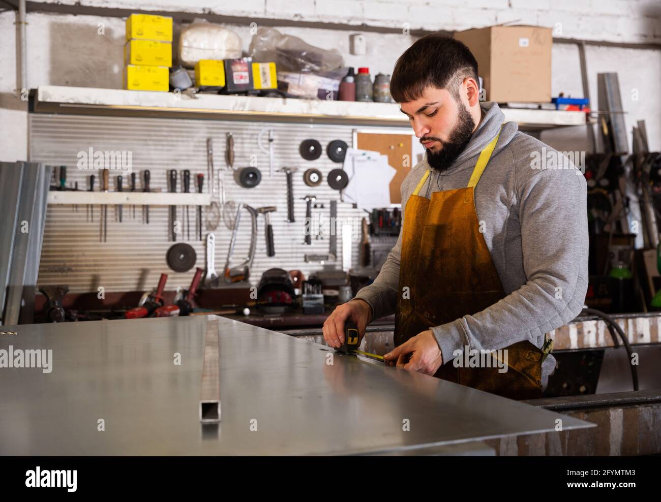 Skilled man worker working with measuring tape in workshop Stock Photo ...
