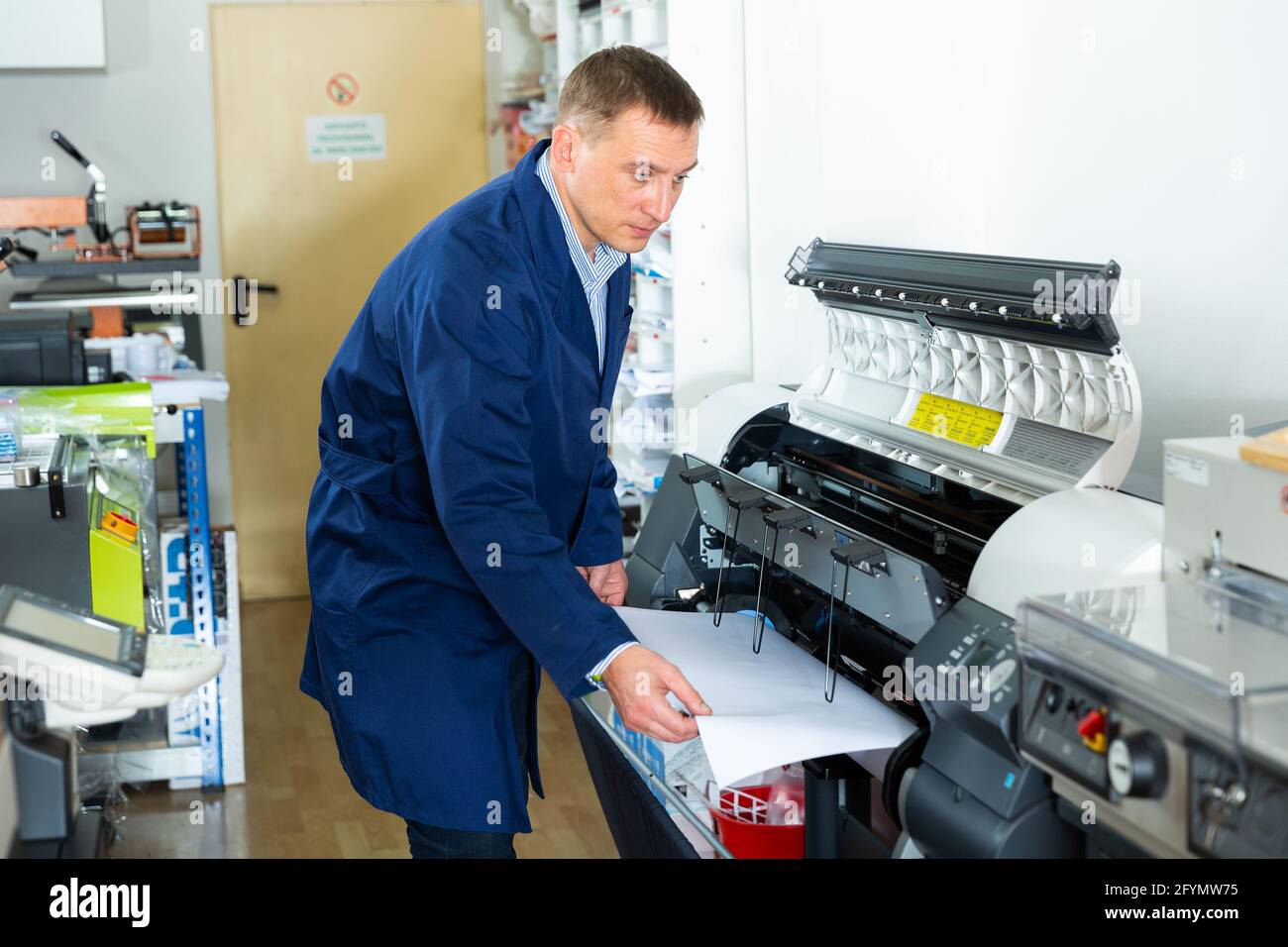 Worker loads new roll of paper into the plotter Stock Photo - Alamy