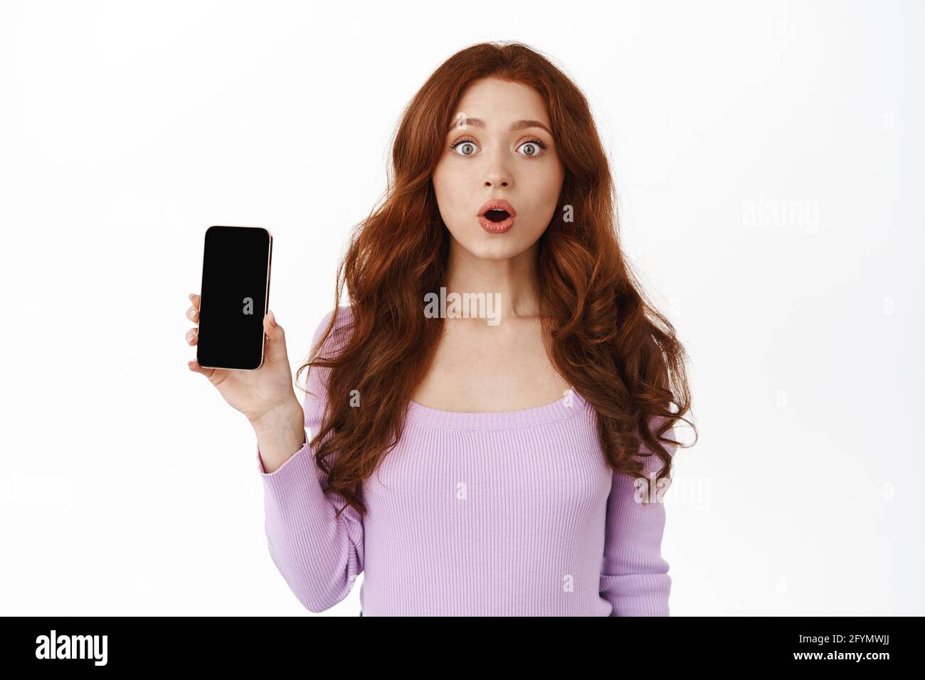 Mobile advertisement. Excited redhead woman gasp wow, shows smartphone ...