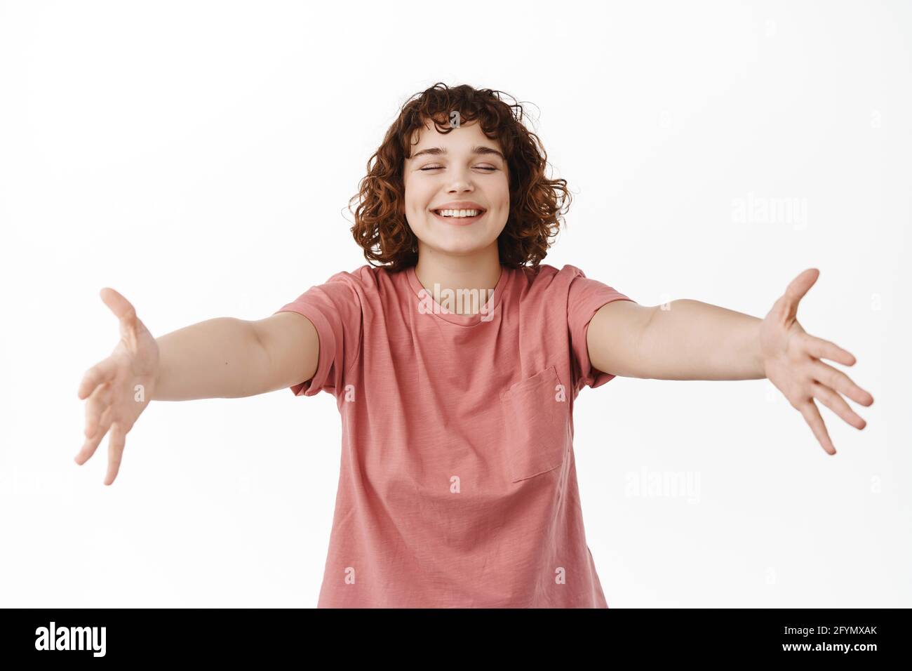 Portrait of cheerful young woman spread hands sideways, reaching for ...
