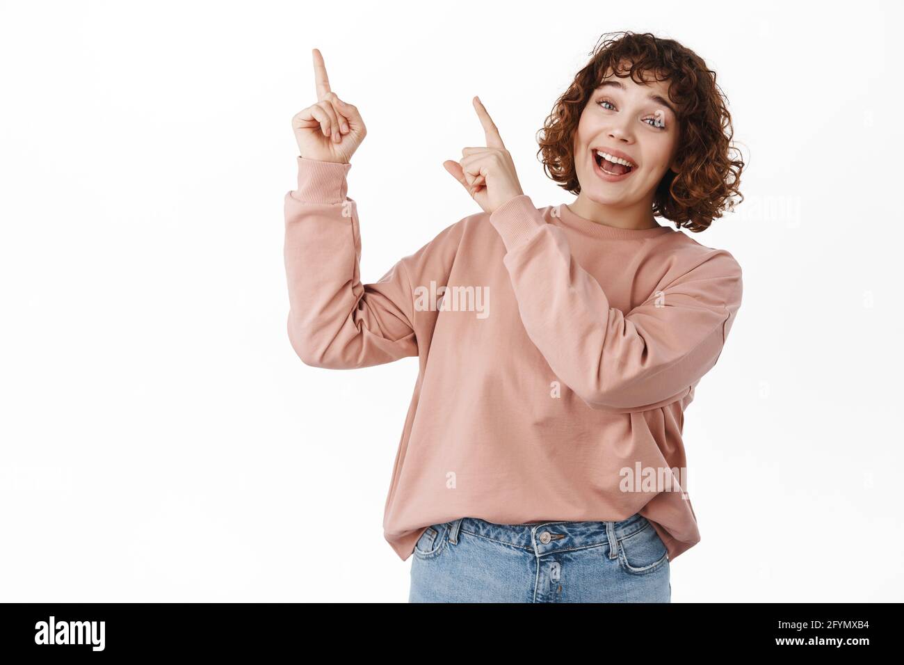 Hey check it out, click here. Smiling cute girl pointing fingers at ...