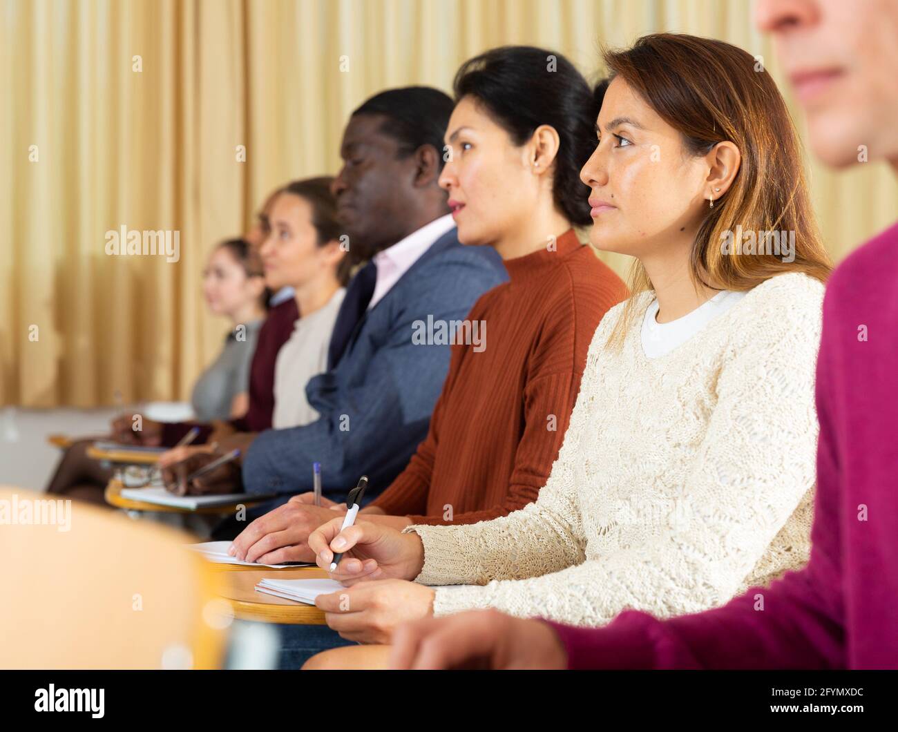 Side view of student group working on lecture in classroom, making ...