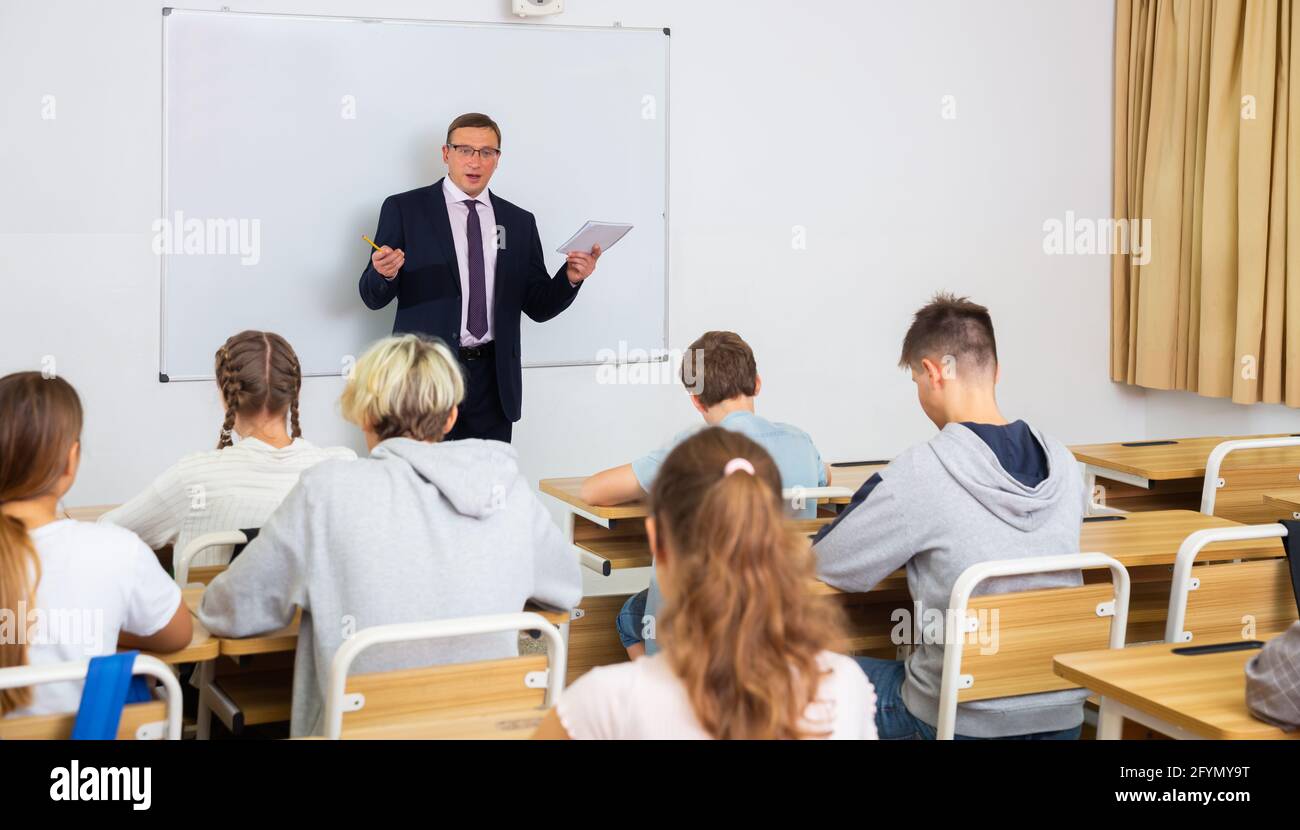 Man teacher with notebook is giving interesting lecture for students in ...