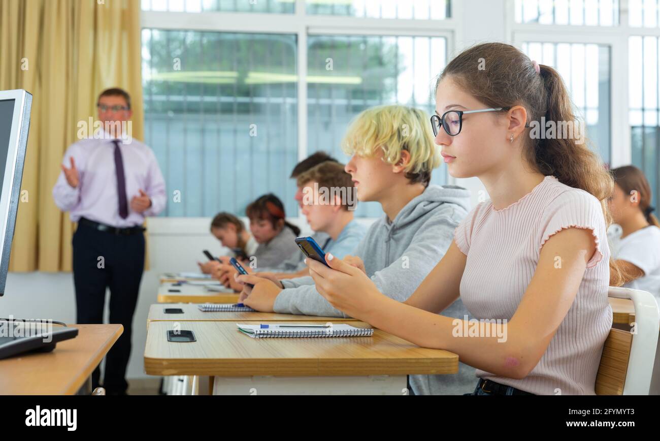 Group of teenage students using smartphones in classroom at school ...