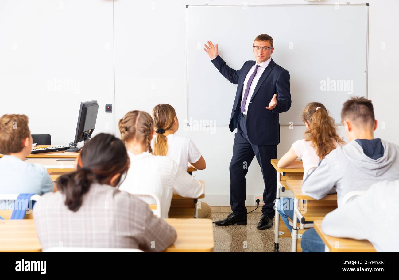 Man teacher with notebook is giving interesting lecture for students in ...