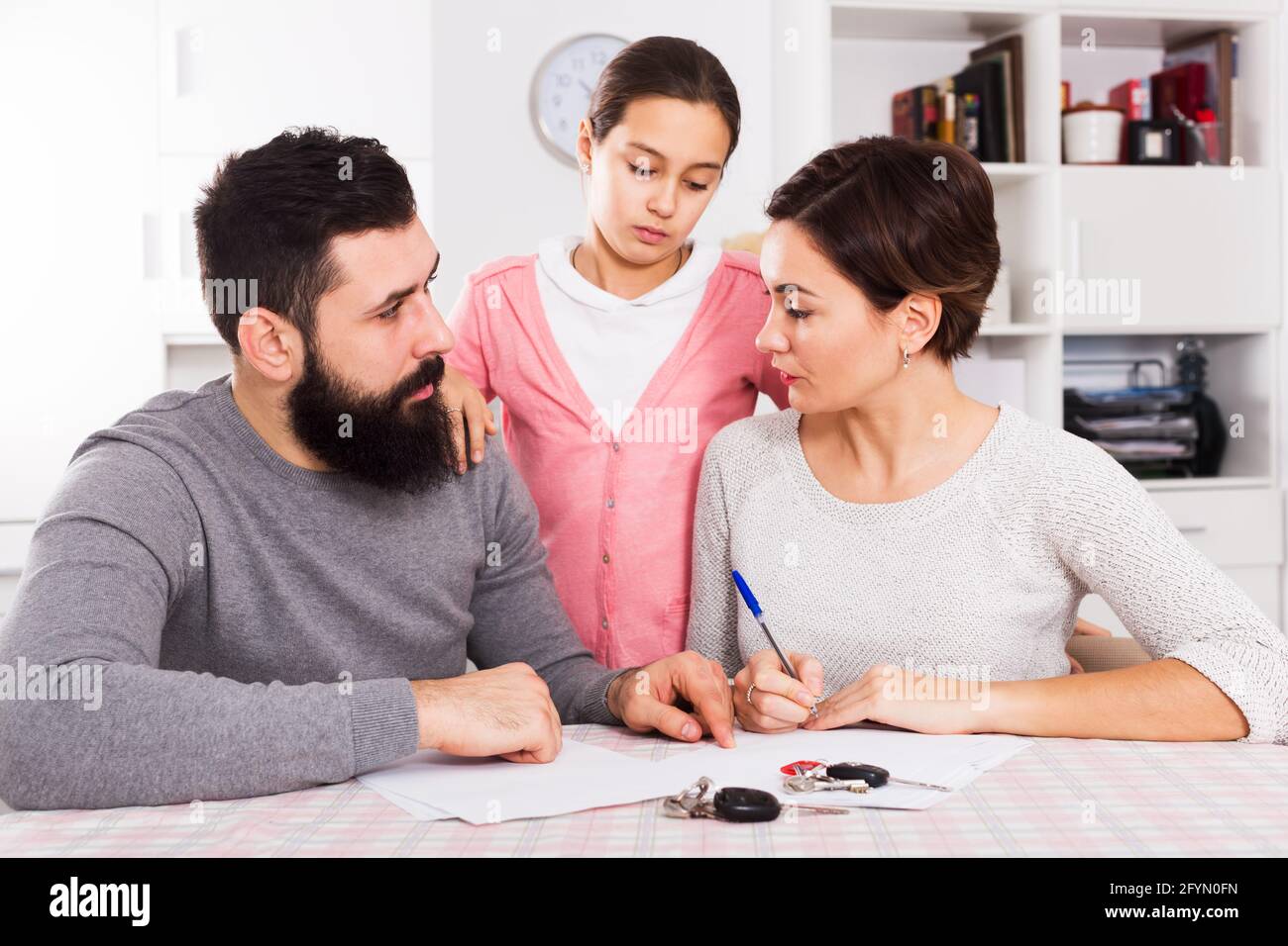 Young parents signing papers for divorce while their daughter at home ...