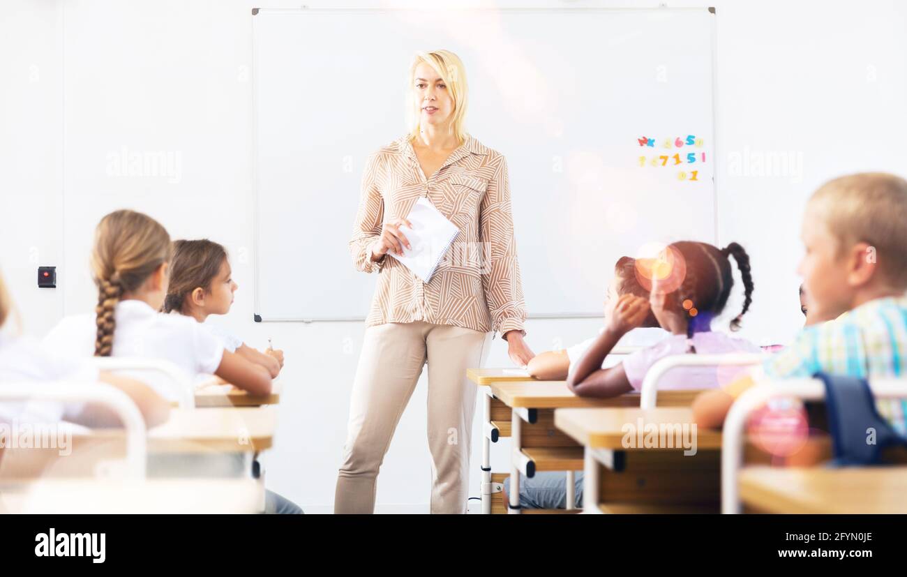 Adult female teacher is giving lecture for primary school students in ...