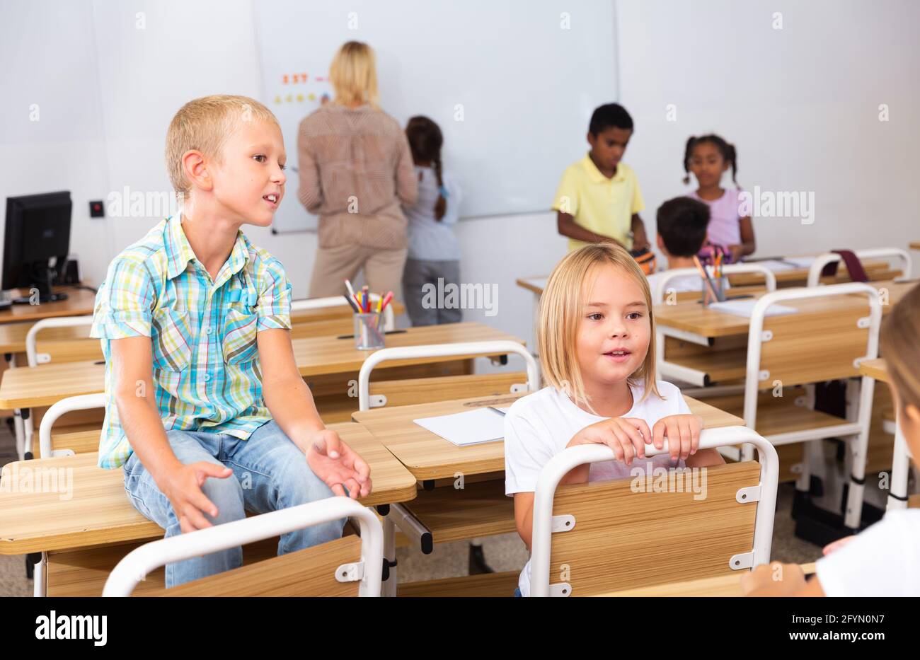 Positive primary school students are talking about homework at the desk ...