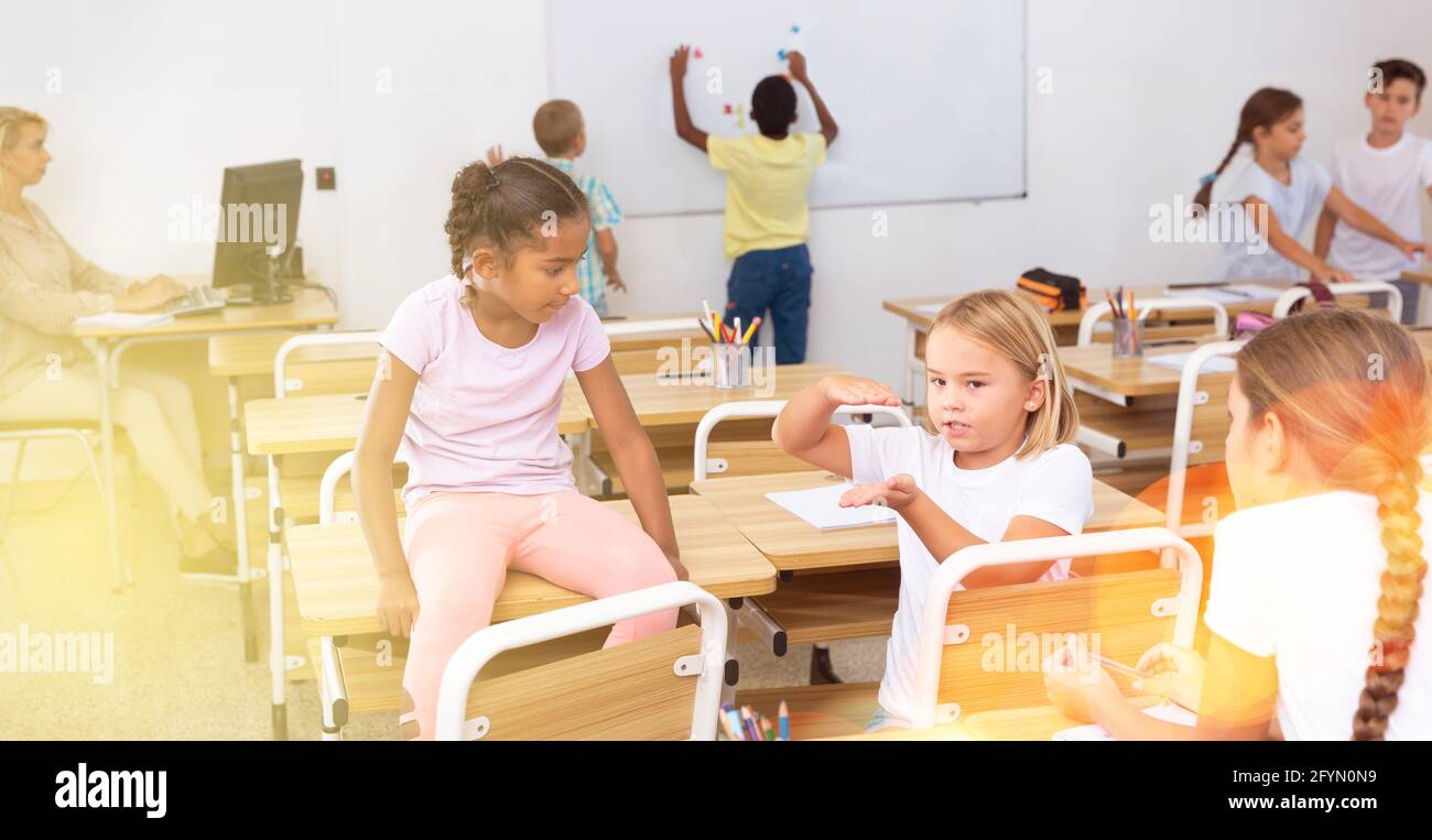 Positive primary school students are talking about homework at the desk ...